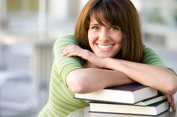 Femme souriante se penchant sur les manuels scolaires | Sheknows.ca