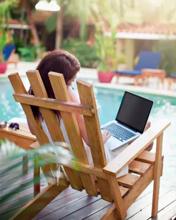 Mujer que trabaja en la computadora en la piscina