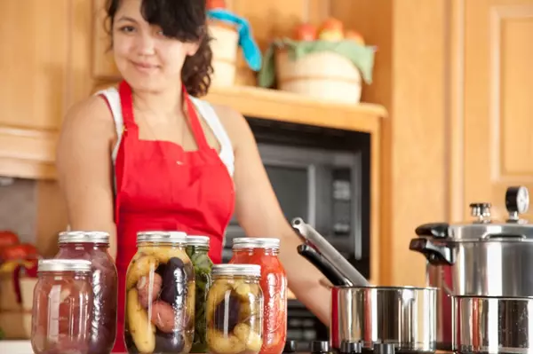 Femme mettant des légumes en conserve à la maison