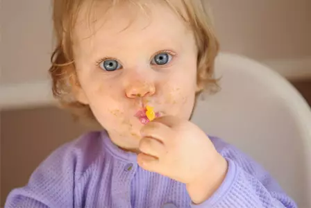 Maža mergaitė valgo kietą maistą