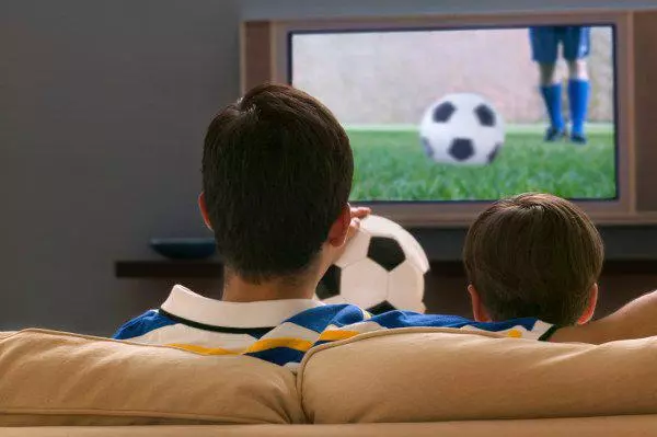 باپ اور بیٹا ٹی وی پر فٹ بال دیکھ رہے ہیں۔