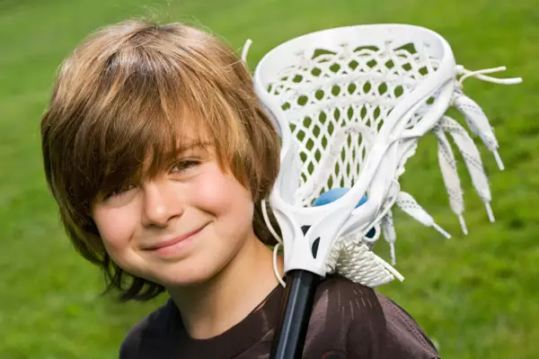 glad, frisk pojke som spelar lacrosse