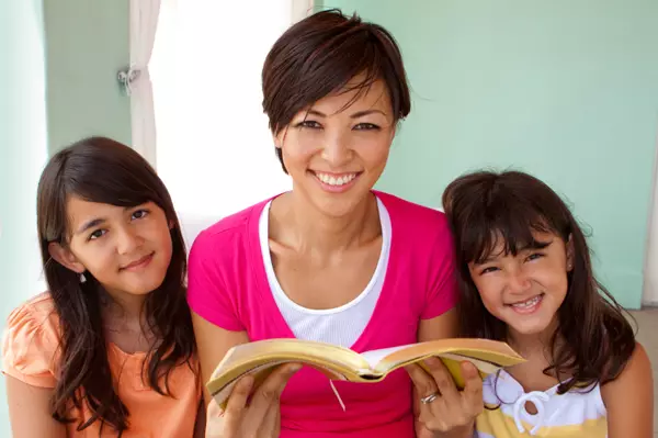 Mutter und zwei Kinder, die glücklich ein Buch lesen