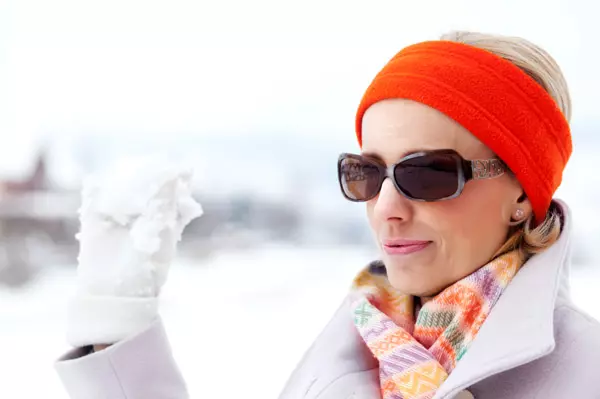 Femme portant des lunettes de soleil tout en jouant dans la neige