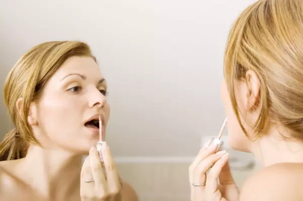 Wanita menggunakan pengilat bibir