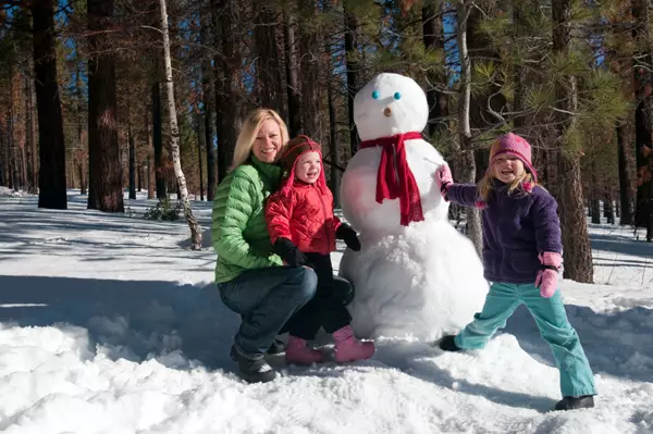 Mare construint un ninot de neu amb nens